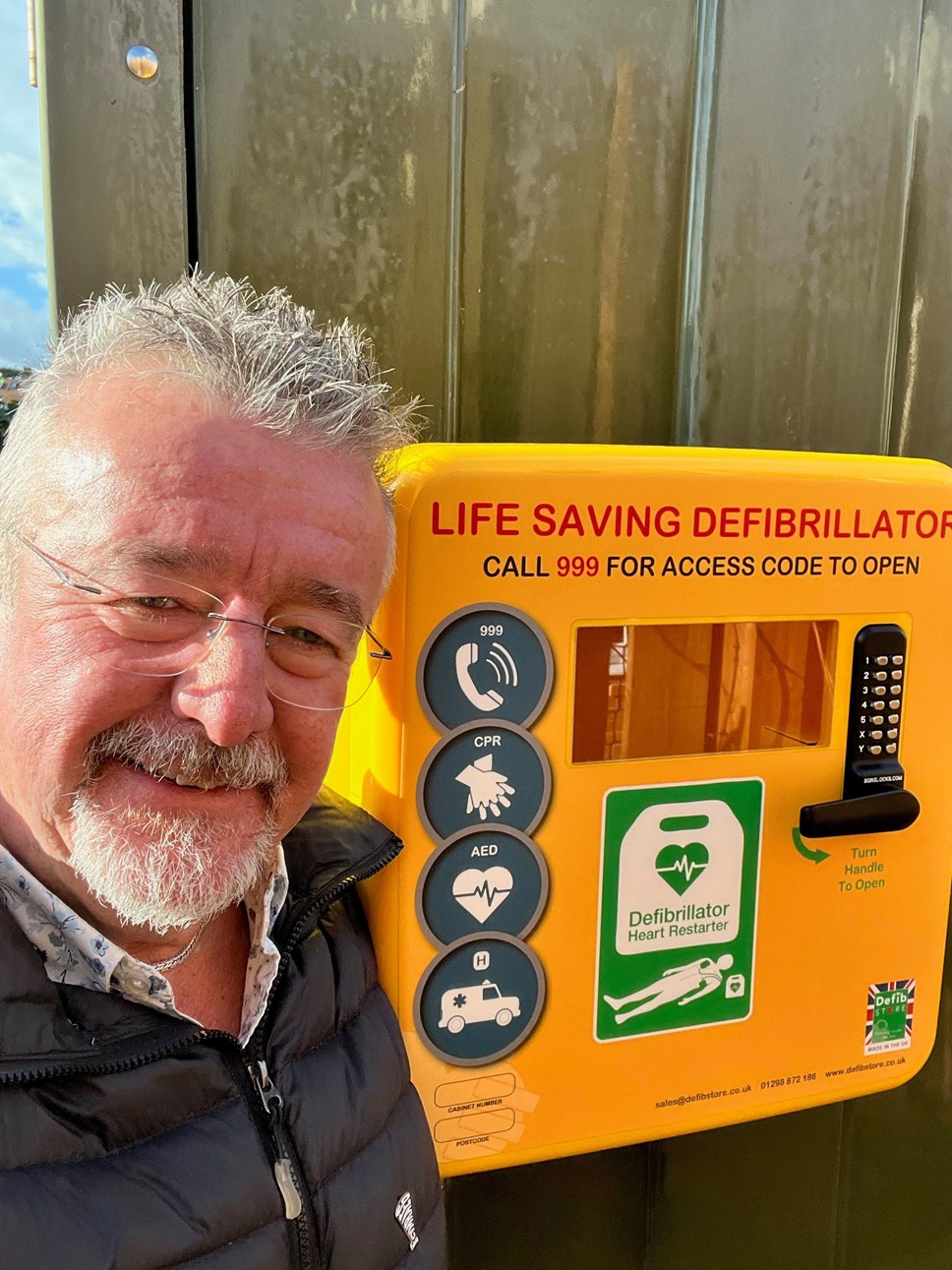 Neville Eden with defibrillator cabinet | Welsh Government News